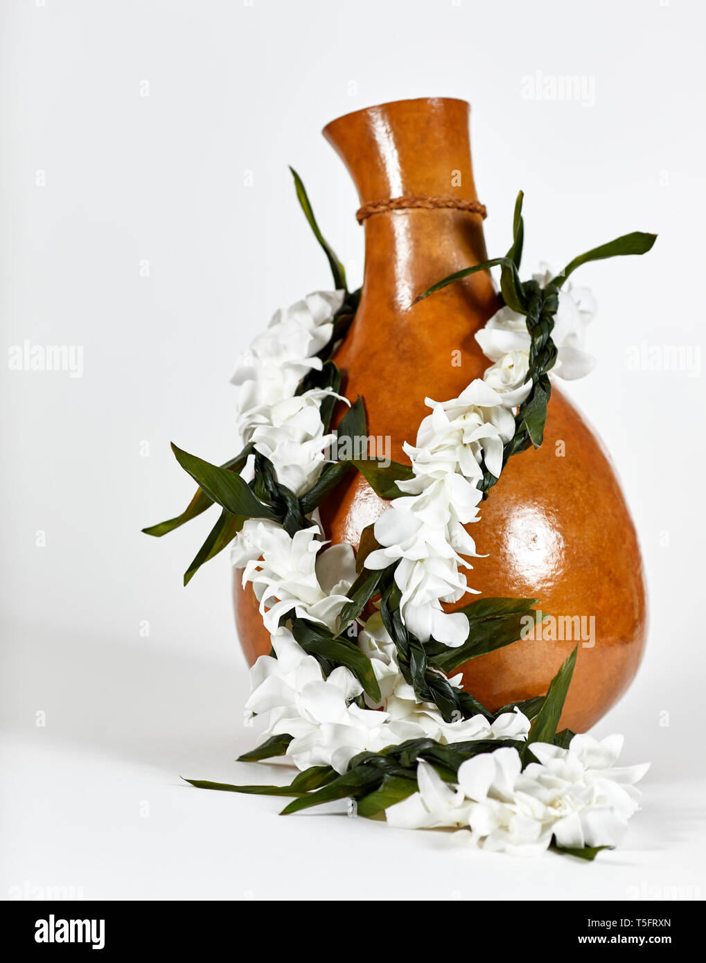 White flower Hawaiian lei with green twisted ti leaf lei laying on an ...