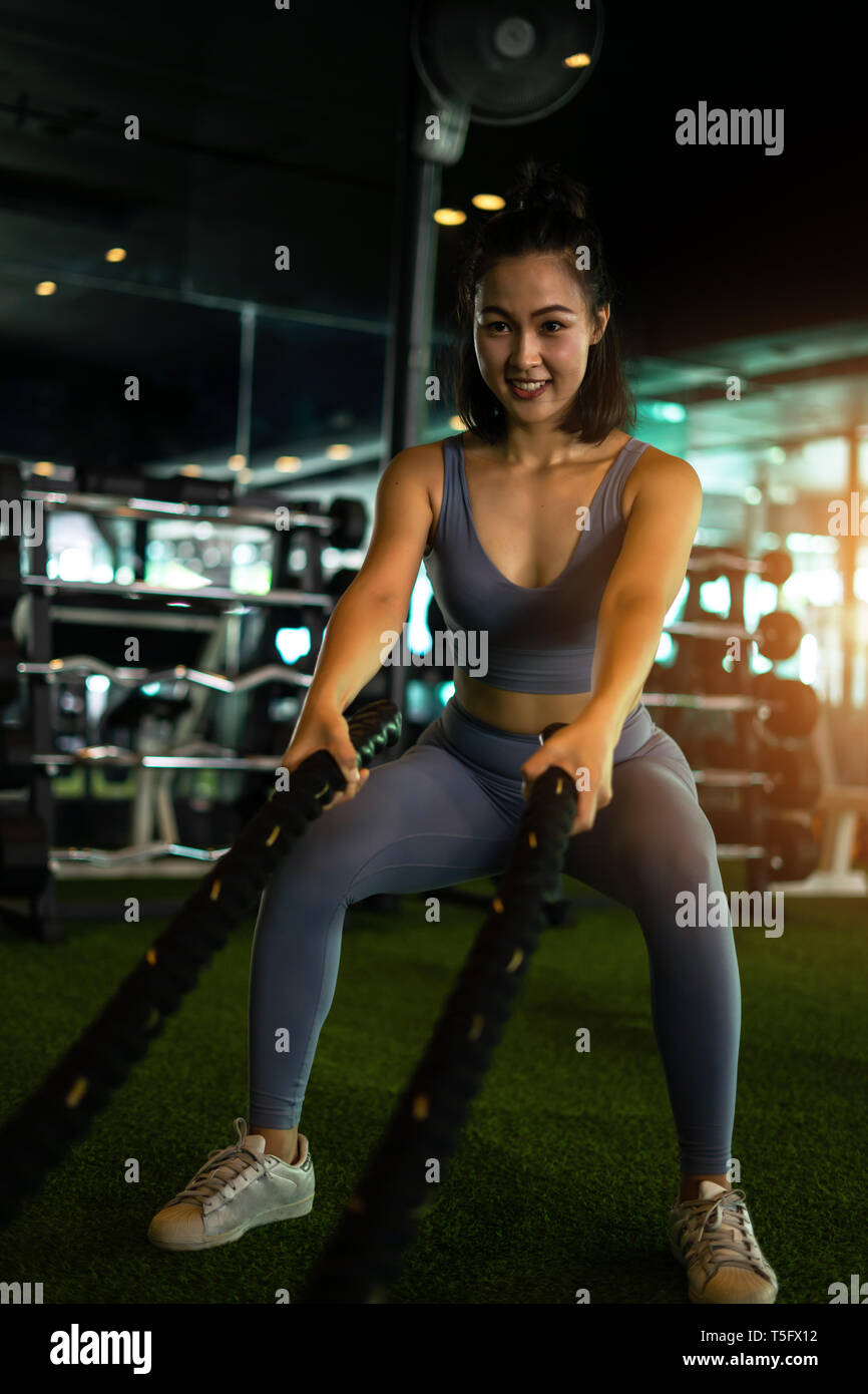 Woman with battle rope battle ropes exercise in the fitness gym ...