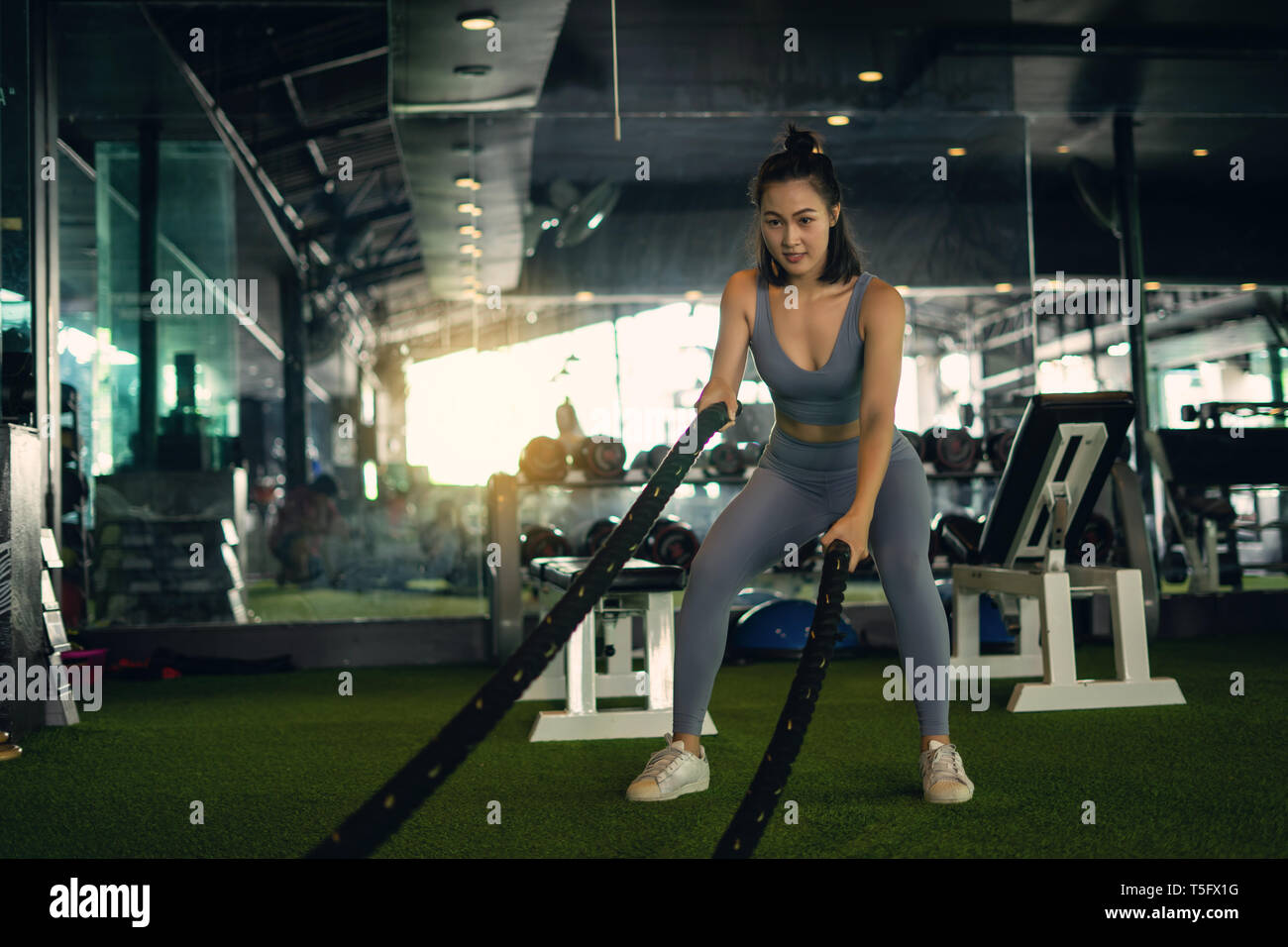 Woman with battle rope battle ropes exercise in the fitness gym ...