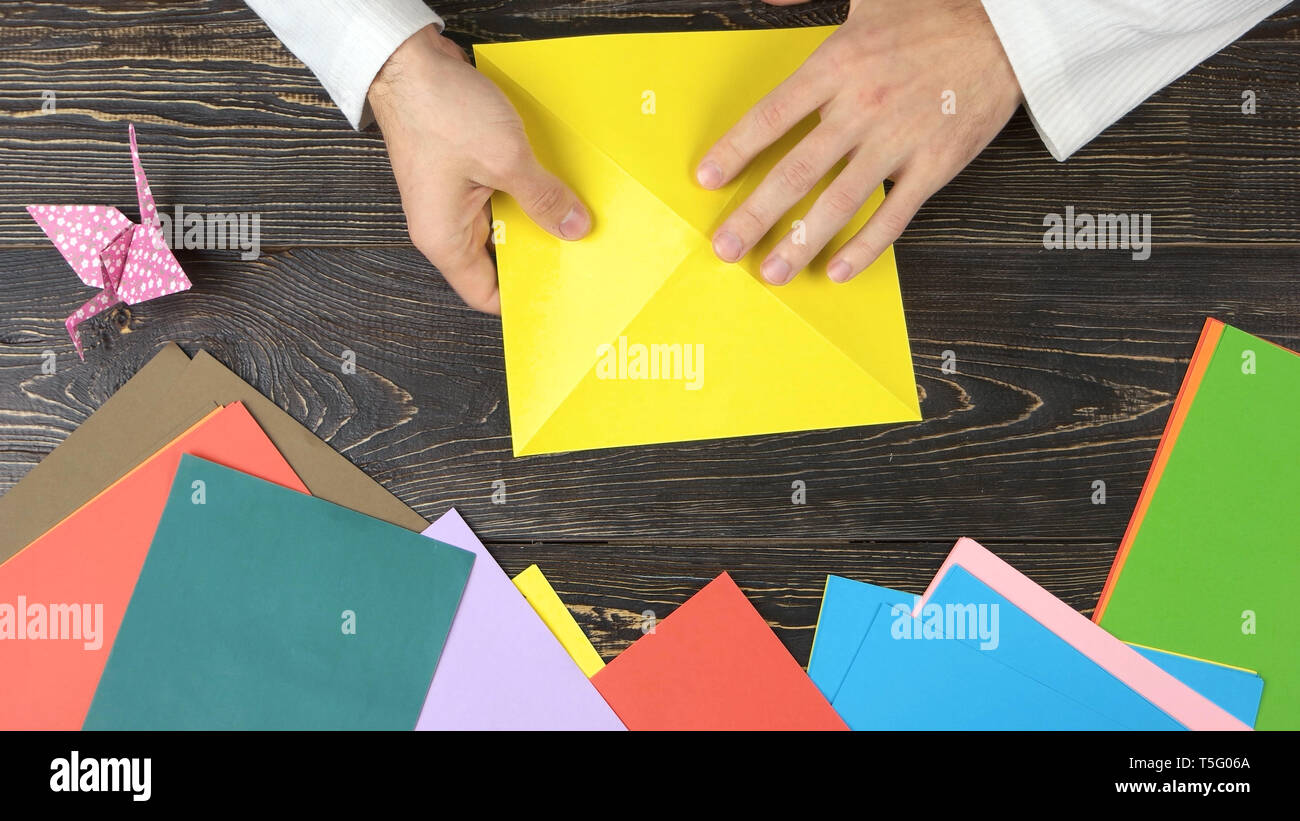 Man folding paper as triangle Stock Photo - Alamy