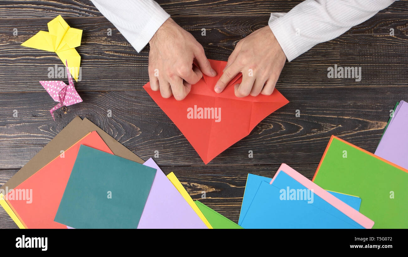 Male hands folding red paper sheet Stock Photo - Alamy
