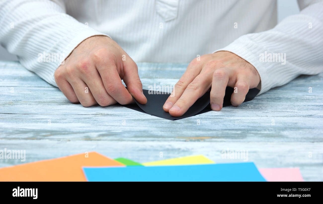 Hands folding black paper sheet Stock Photo - Alamy