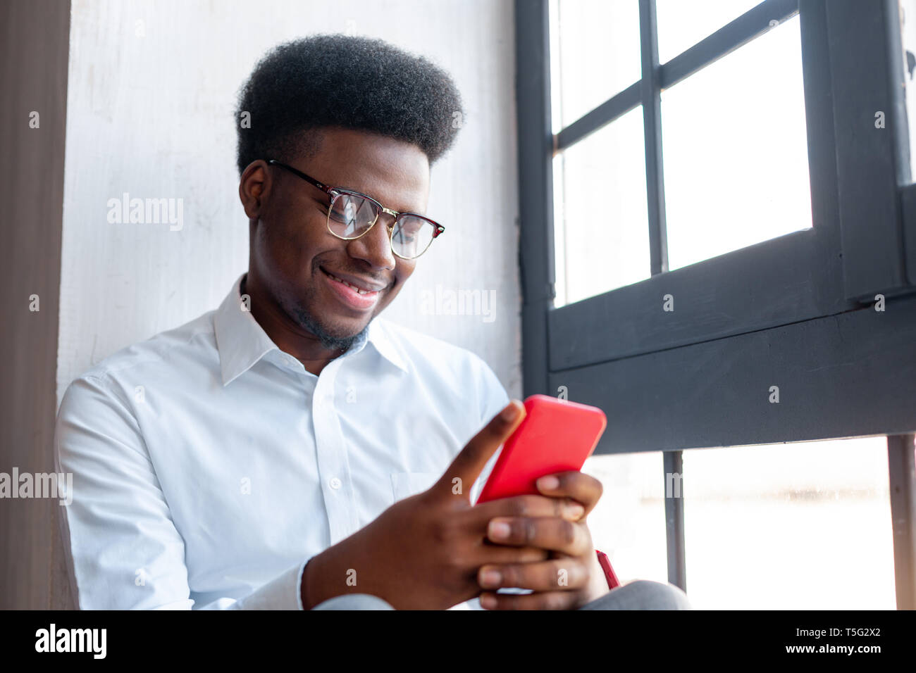 Joyful positive young man using his smartphone Stock Photo - Alamy