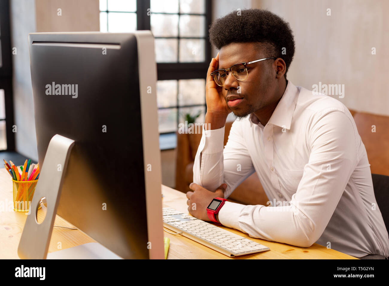 Serious gloomy young man holding his cheek Stock Photo - Alamy