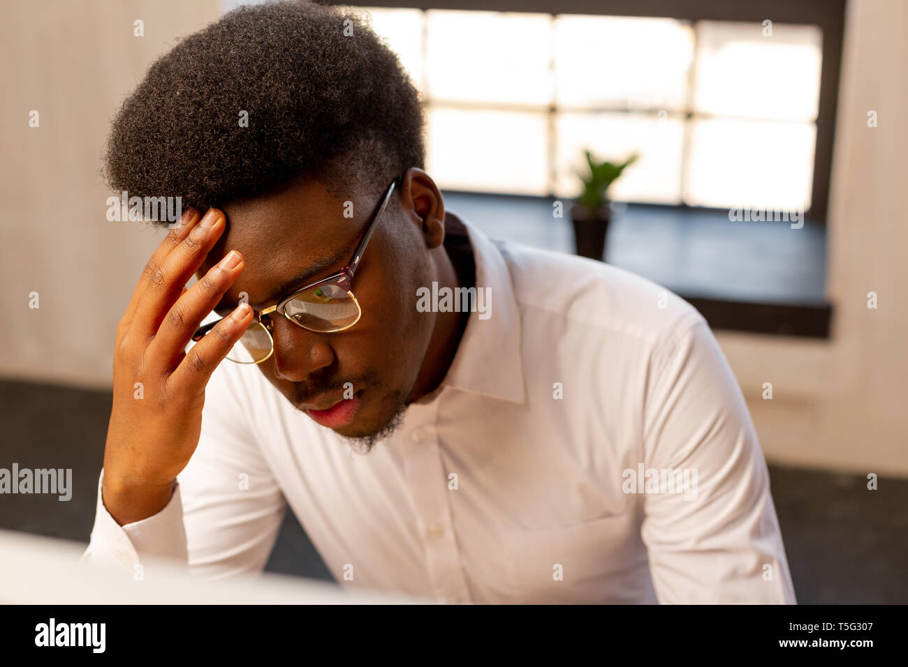 Serious nice young man touching his forehead Stock Photo - Alamy