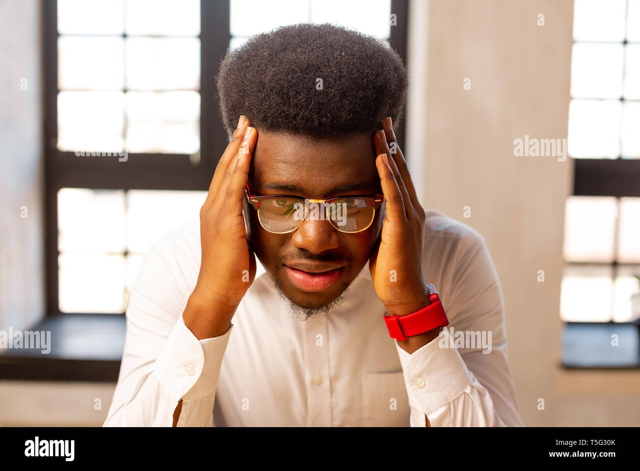 Unhappy cheerless young man holding his head Stock Photo - Alamy