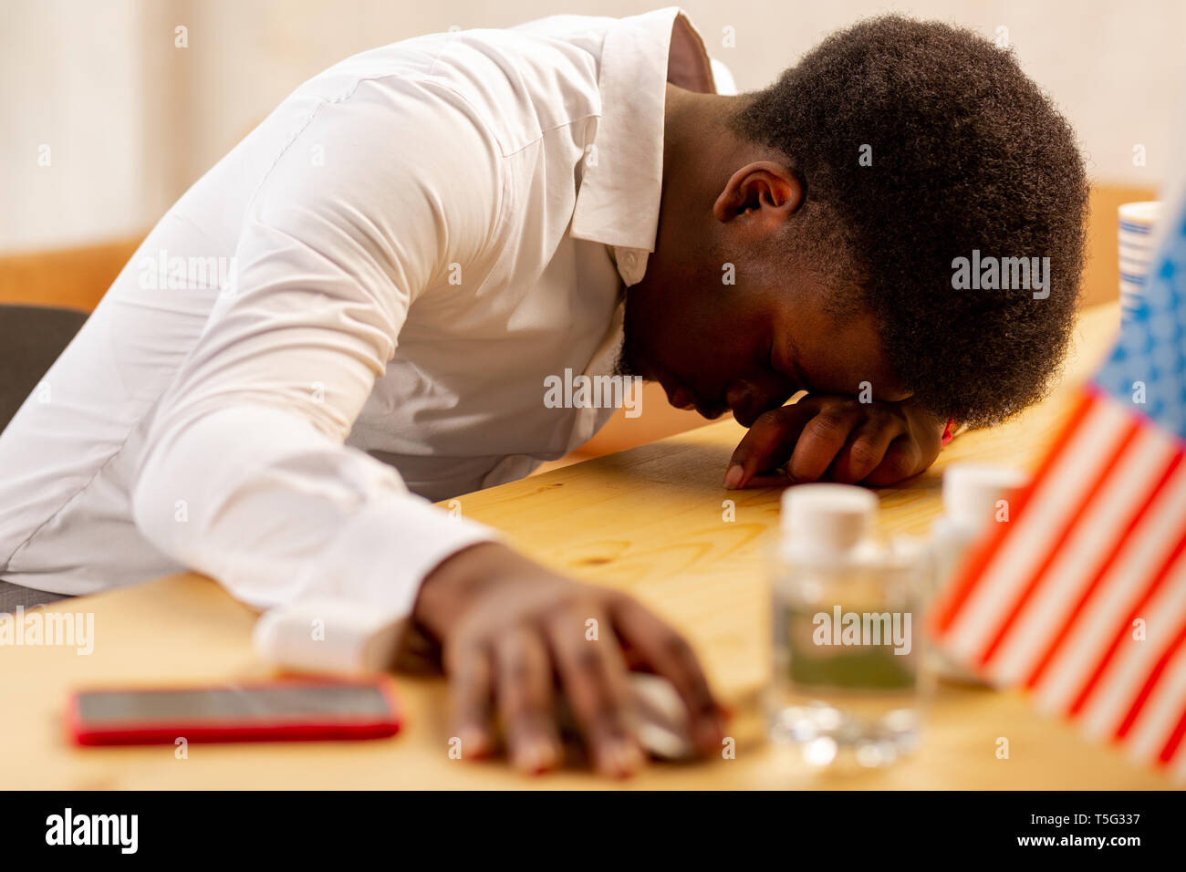Tired young man putting his hand on the table Stock Photo - Alamy