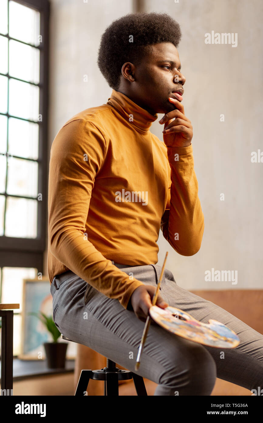 Pleasant creative man thinking about his painting Stock Photo - Alamy