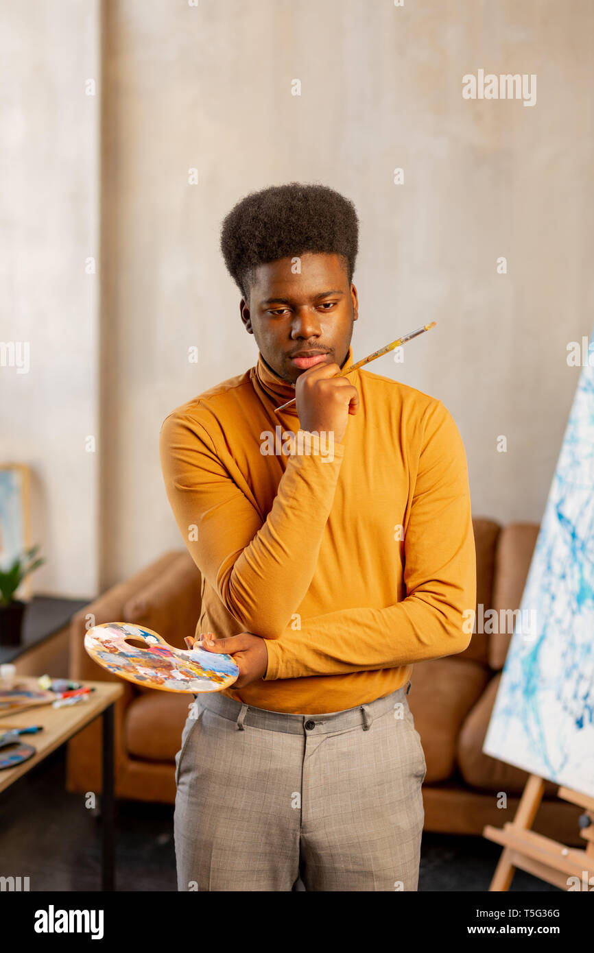 Creative young man thinking about his painting Stock Photo - Alamy