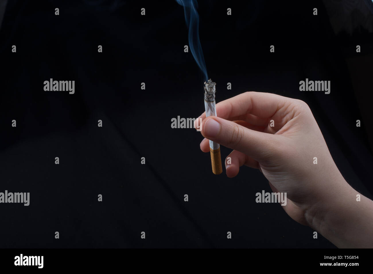 Hand is holding smoking cigarette with smoke around Stock Photo - Alamy
