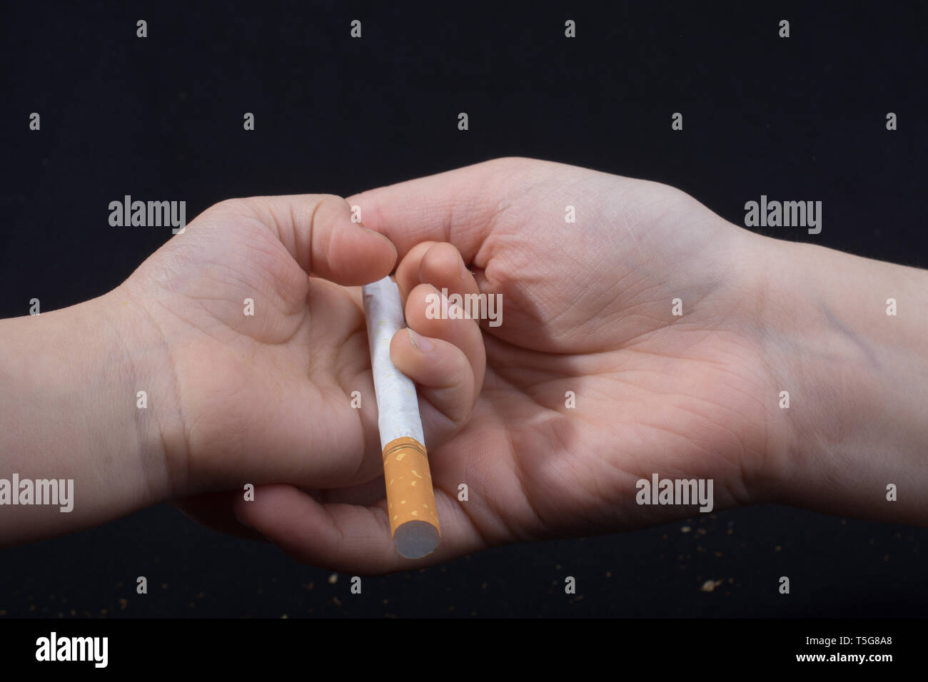 Hand is giving out cigarette on a black background Stock Photo - Alamy