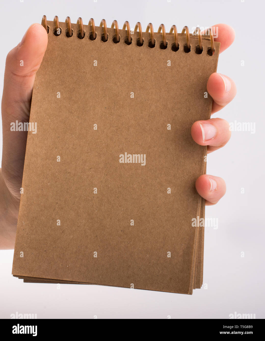 Hand holding brown color notebook on a white background Stock Photo - Alamy
