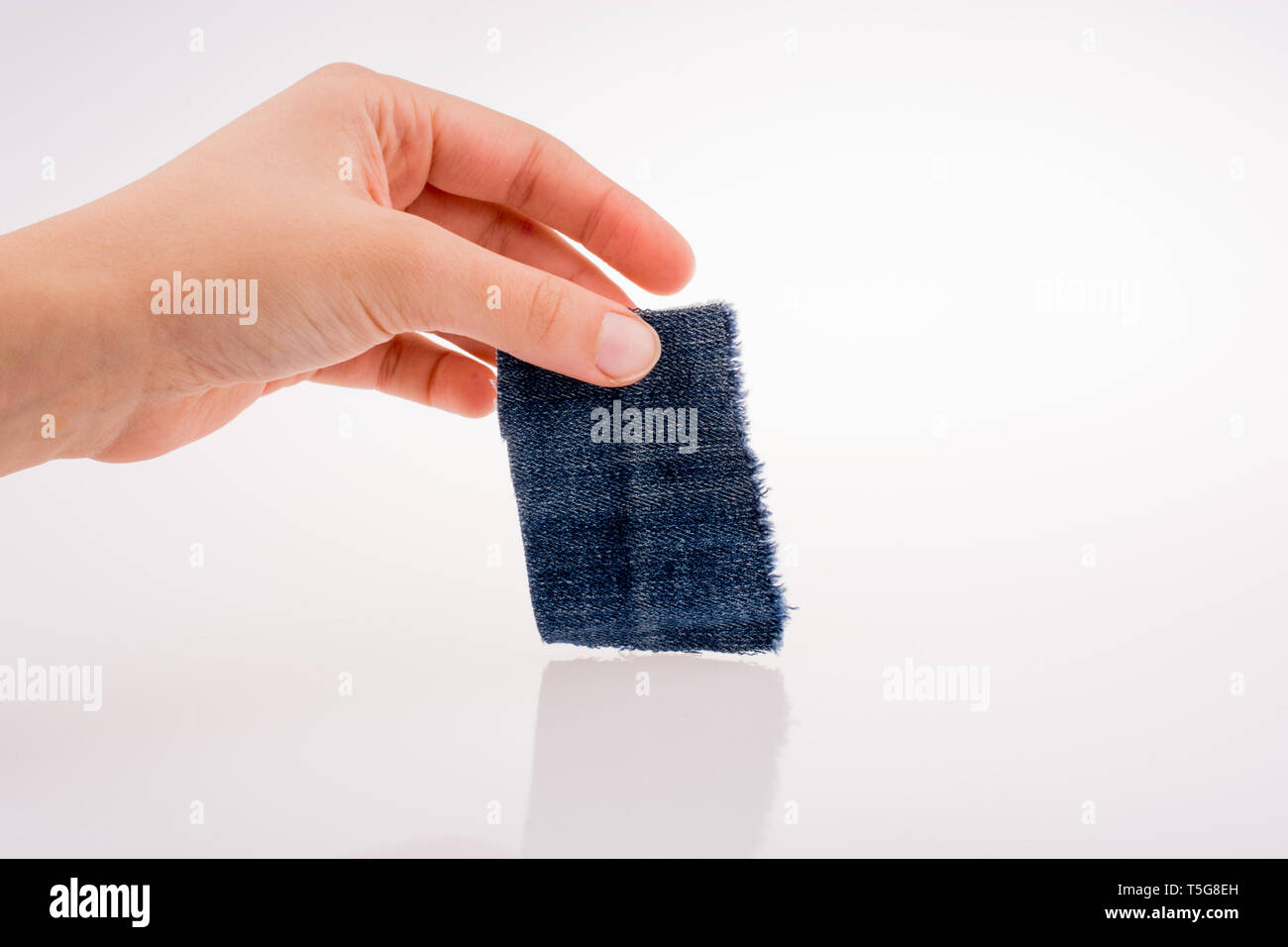 Hand holding a denim fabric piece on white background Stock Photo - Alamy