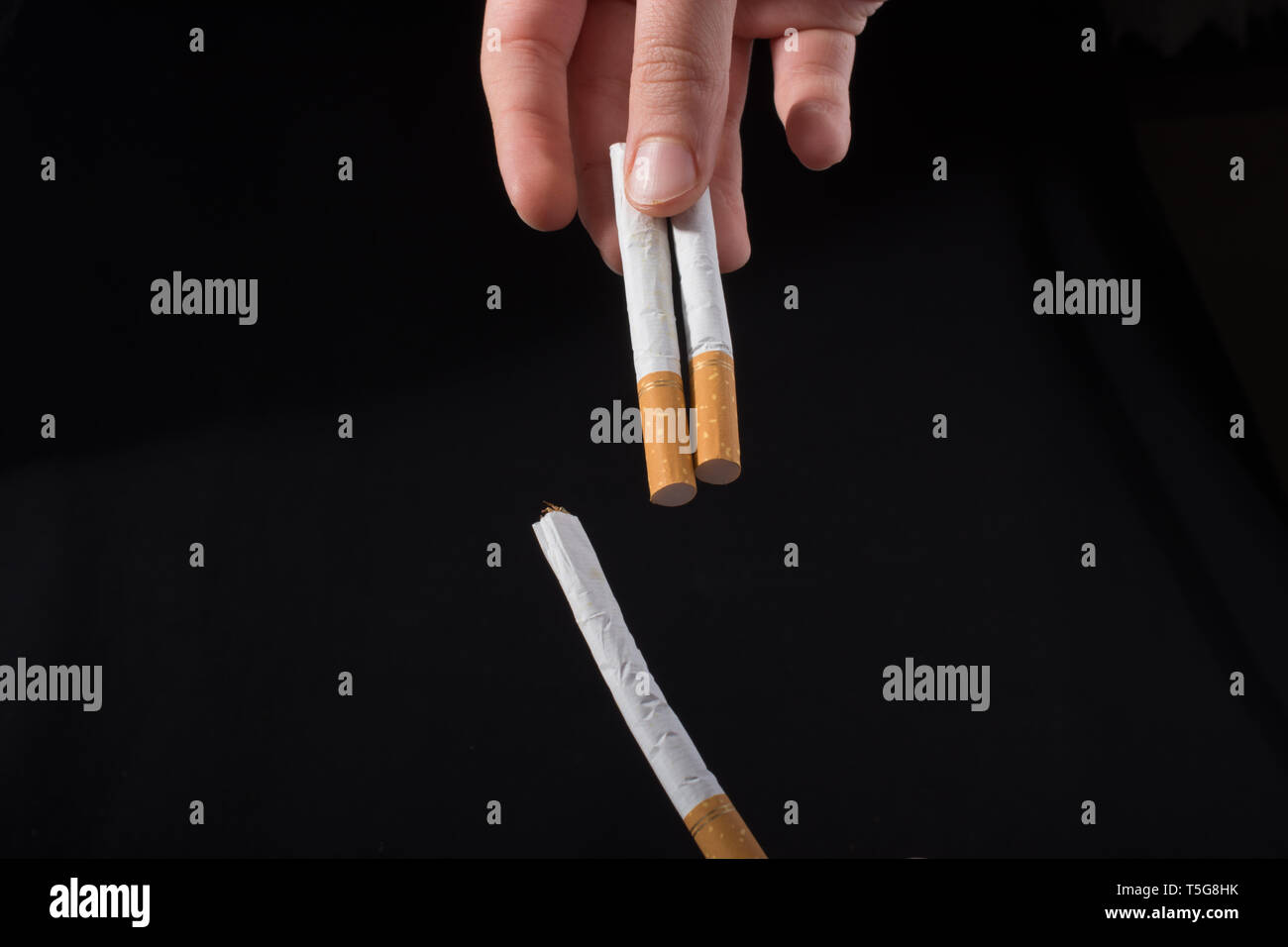 Hand is giving out cigarette on a black background Stock Photo - Alamy