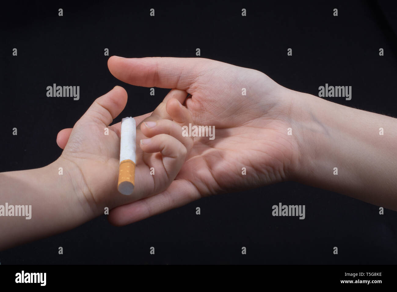 Hand is giving out cigarette on a black background Stock Photo - Alamy