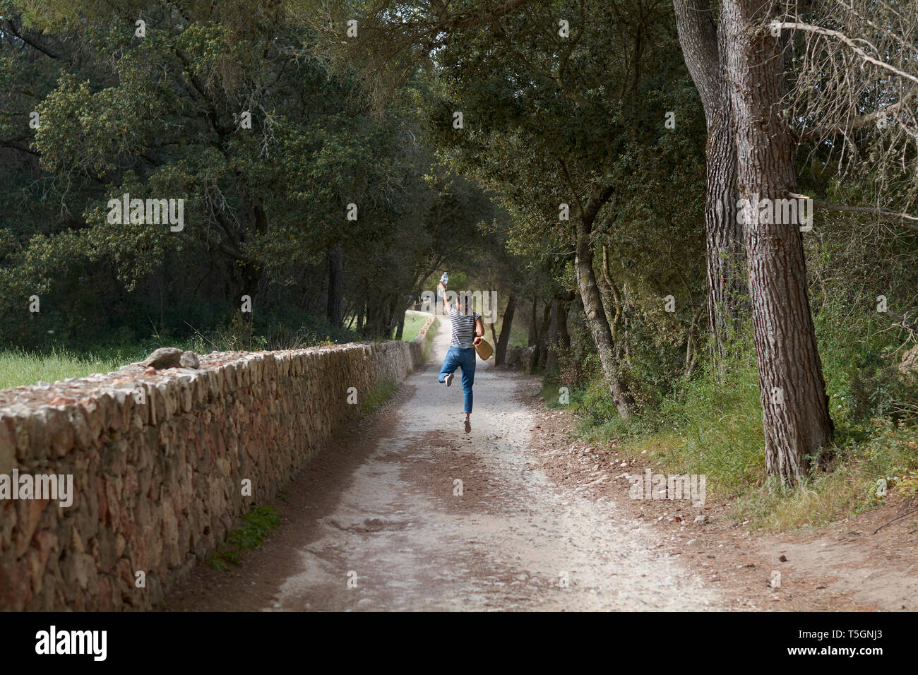 Spain, Menorca, back view of happy young woman jumping in the air Stock ...