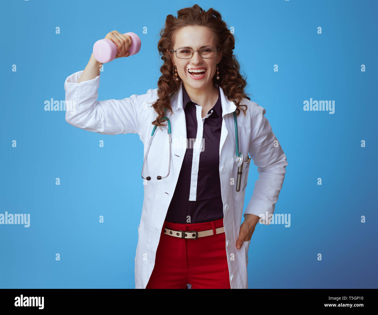 smiling elegant doctor woman in bue shirt, red pants and white medical ...