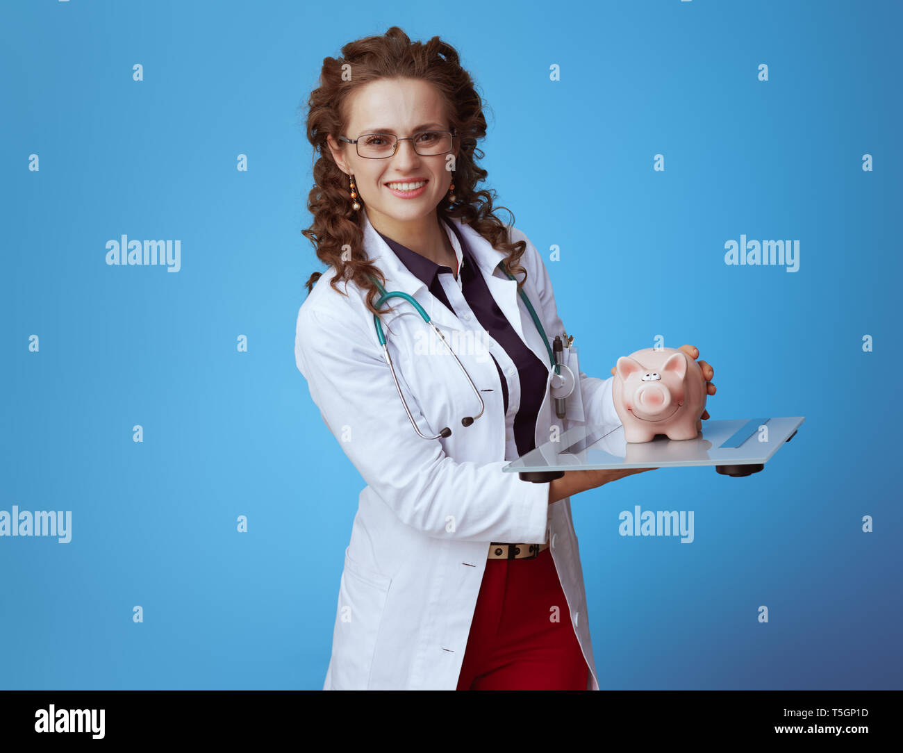 smiling elegant medical doctor woman in bue shirt, red pants and white ...