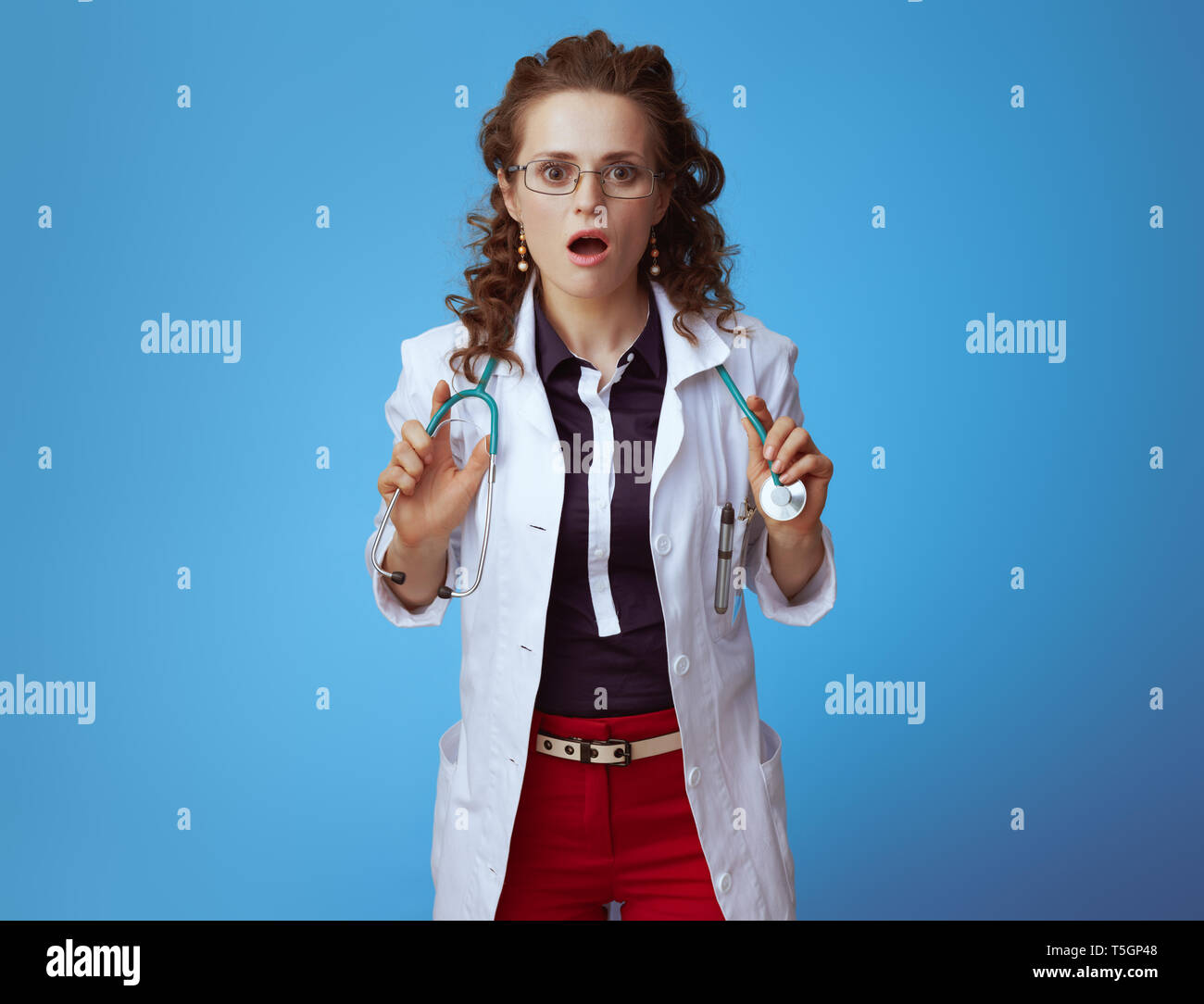 Portrait of surprised elegant medical doctor woman in bue shirt, red ...