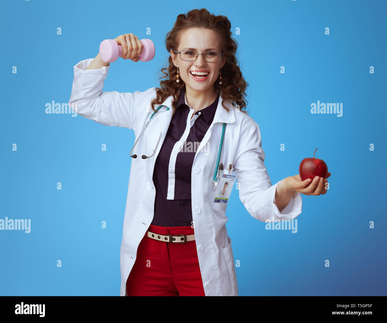 happy modern physician woman in bue shirt, red pants and white medical ...