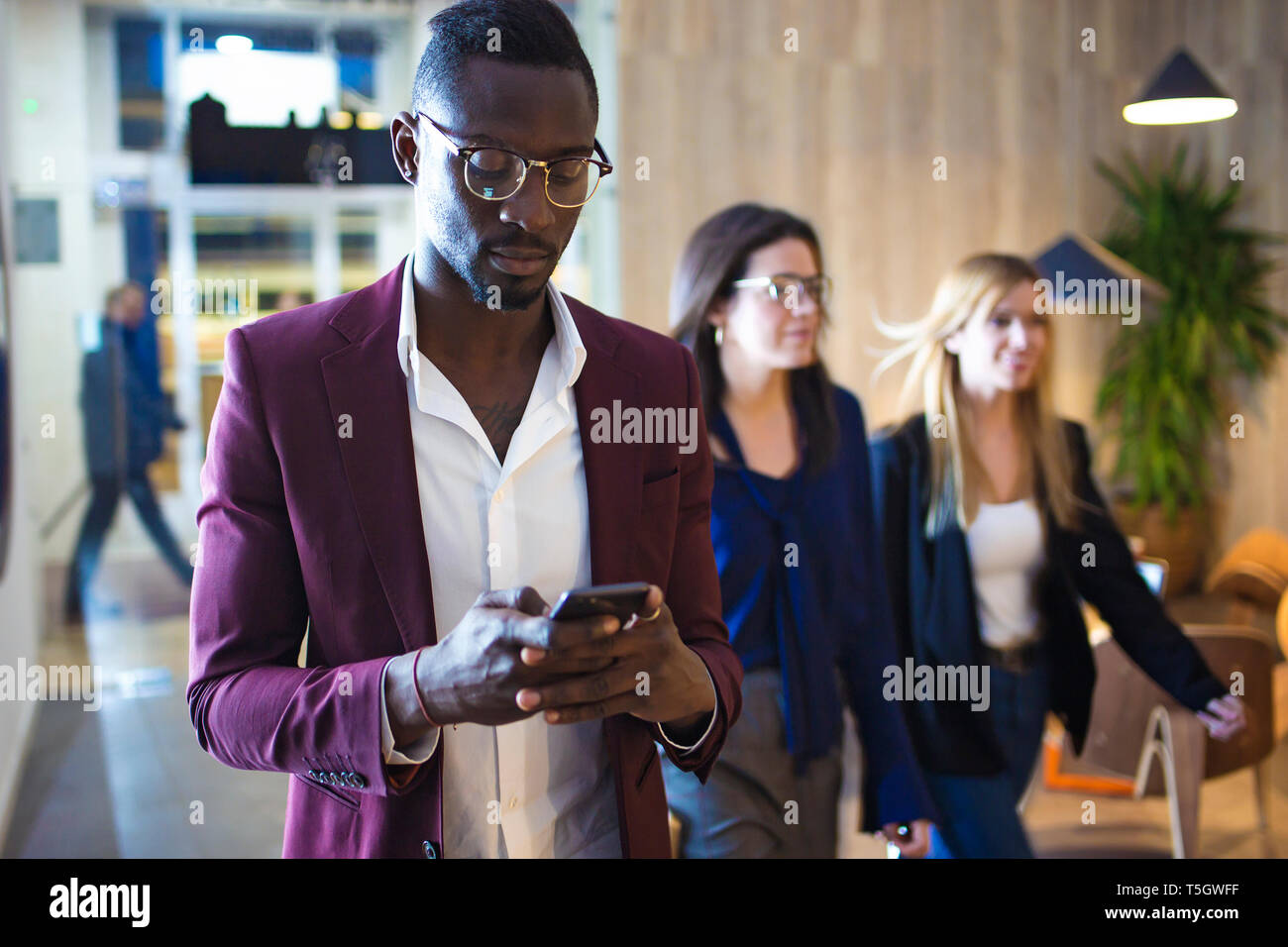 Business people walking in hotel lobby, man using smartphone Stock ...