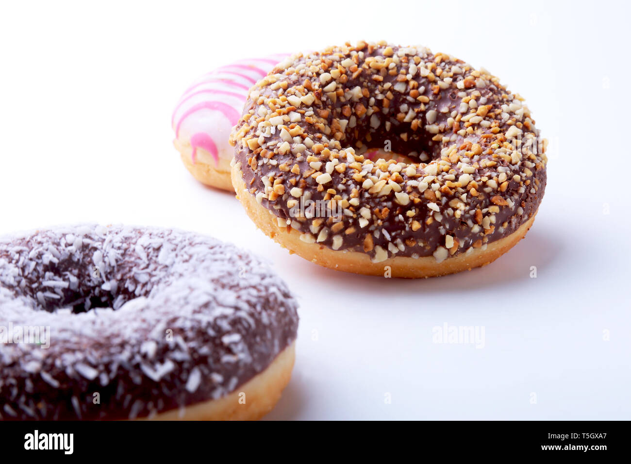 Assorted doughnuts in the glaze, colorful sprinkles and nuts on a white ...