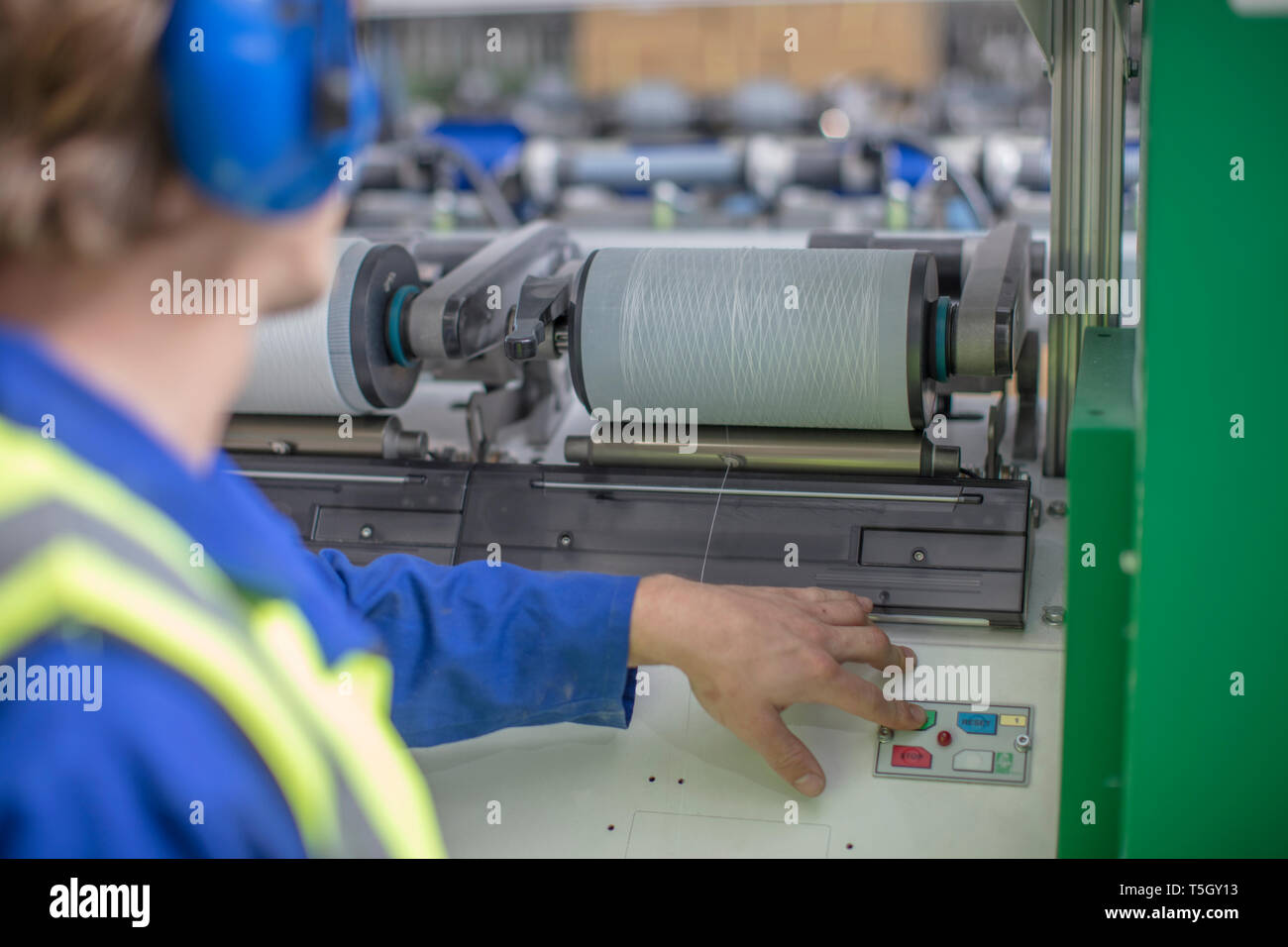 Man wearing ear defenders operating spool machine in factory Stock ...