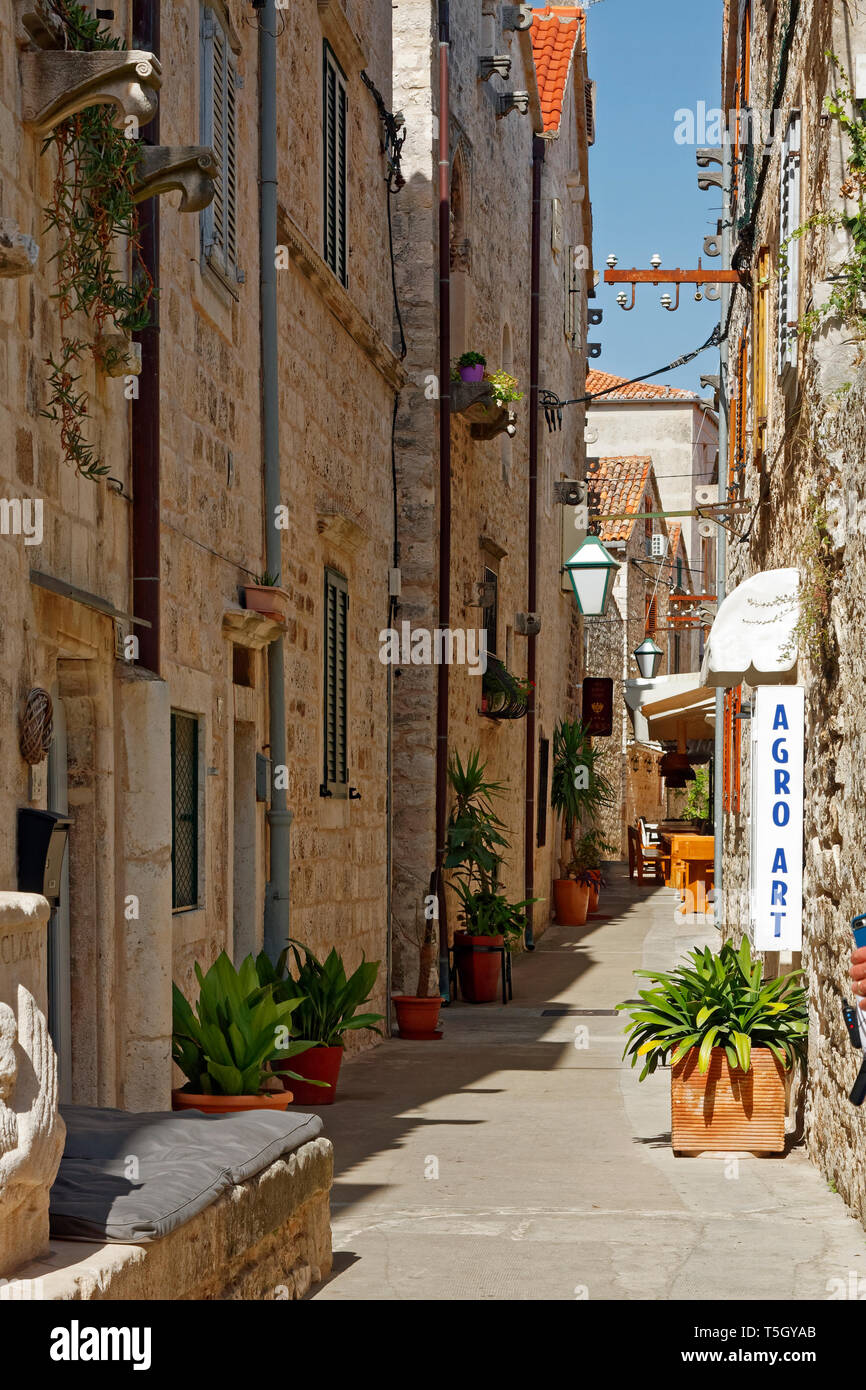narrow pedestrian street; old stone buildings; potted plants, city ...