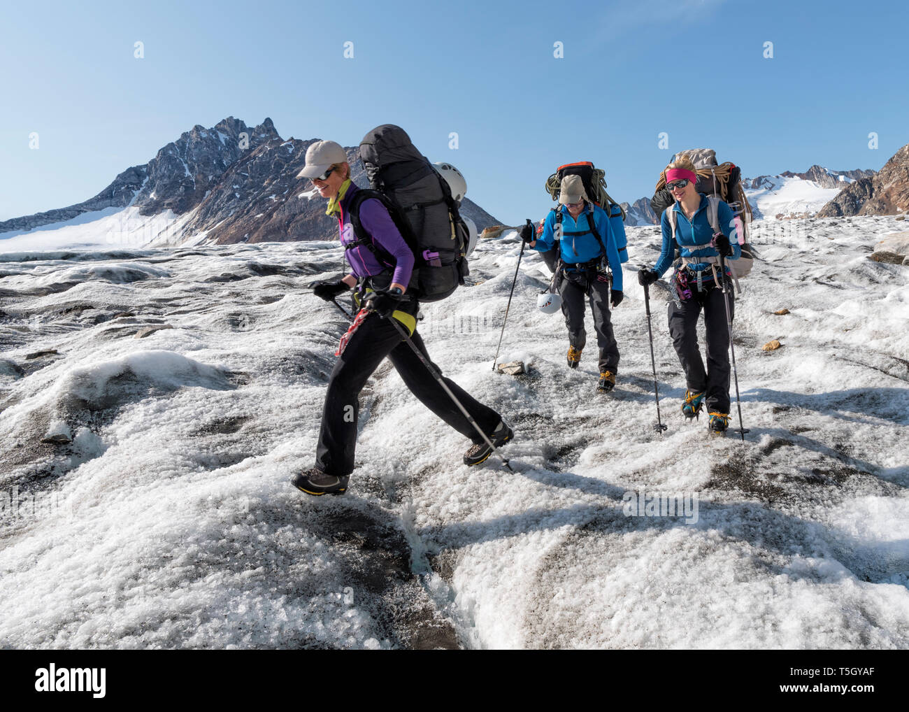 Greenland, Sermersooq, Kulusuk, Schweizerland Alps, three people walking in snowy mountainscape ...