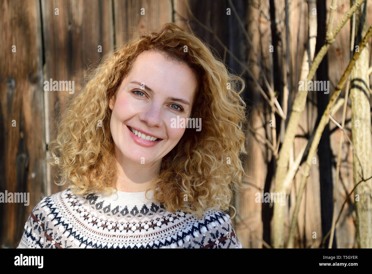 Blonde woman with curly hair smiling, norwegian sweater Stock Photo - Alamy