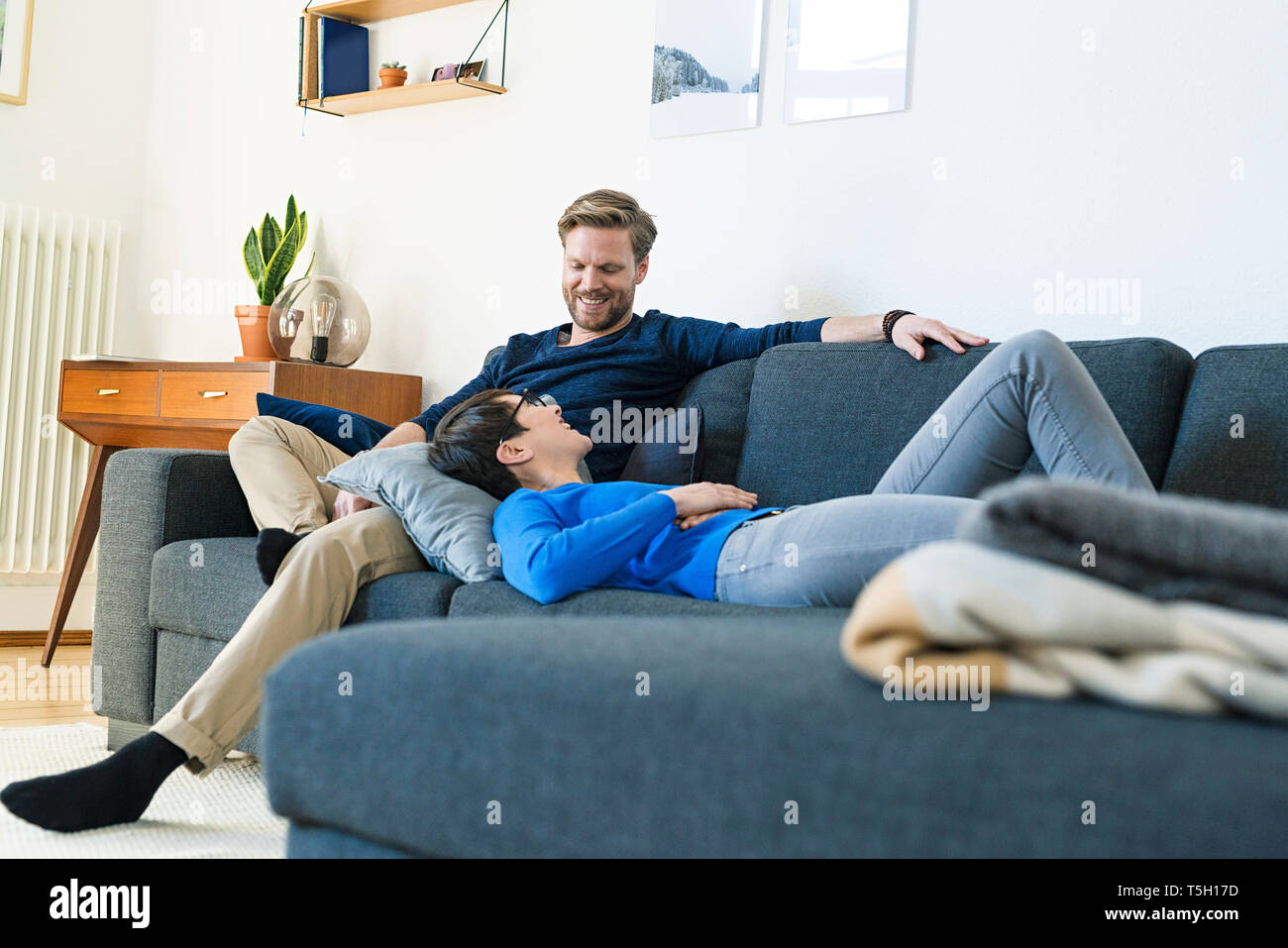 Happy casual couple relaxing on lounge couch in their modern living ...