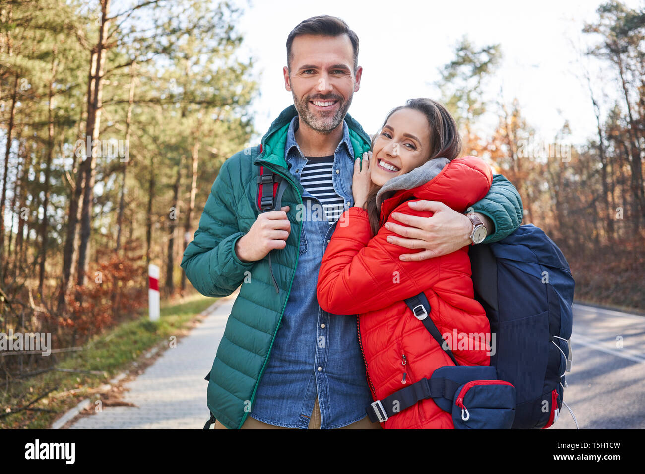 Portrait of happy couple embracing on a road in the woods during ...