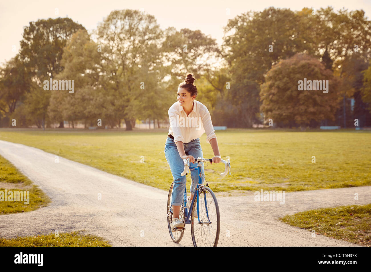 Young woman riding bike at a park Stock Photo - Alamy