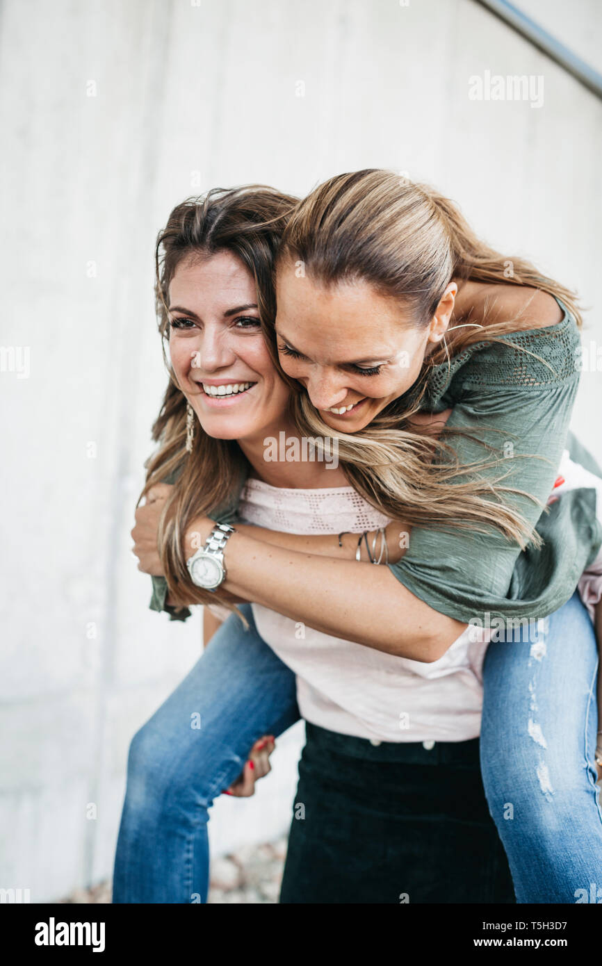 Portrait of laughing woman giving her friend a piggyback ride Stock ...