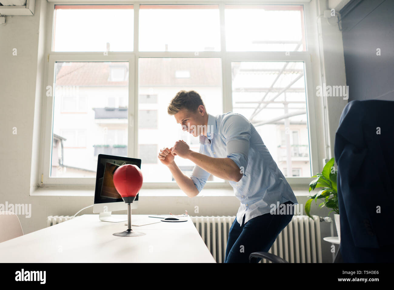 Young businessman at desk in office boxing with punching ball Stock ...