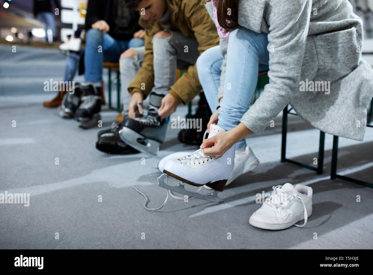 Friends putting on ice skates at an ice rink Stock Photo - Alamy