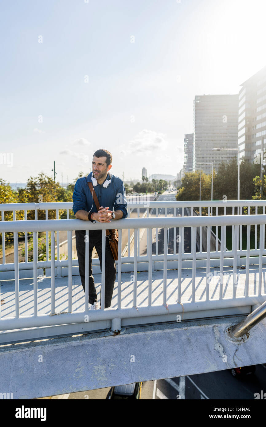 Man leaning on railing of footbridge looking at distance Stock Photo ...