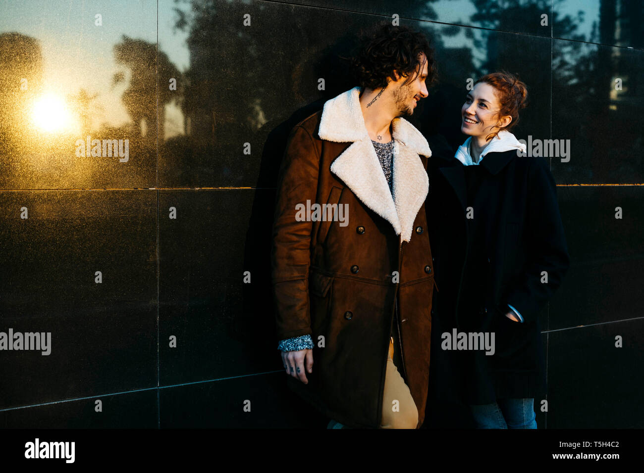 Couple at a black wall with reflections talking to each other Stock ...