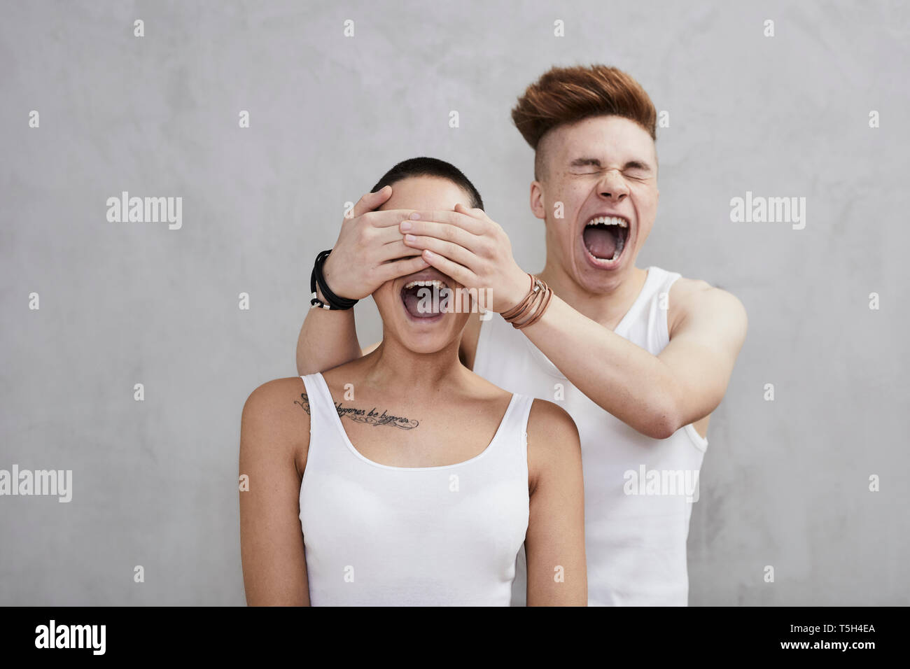 Portrait of screaming young couple wearing vests Stock Photo - Alamy