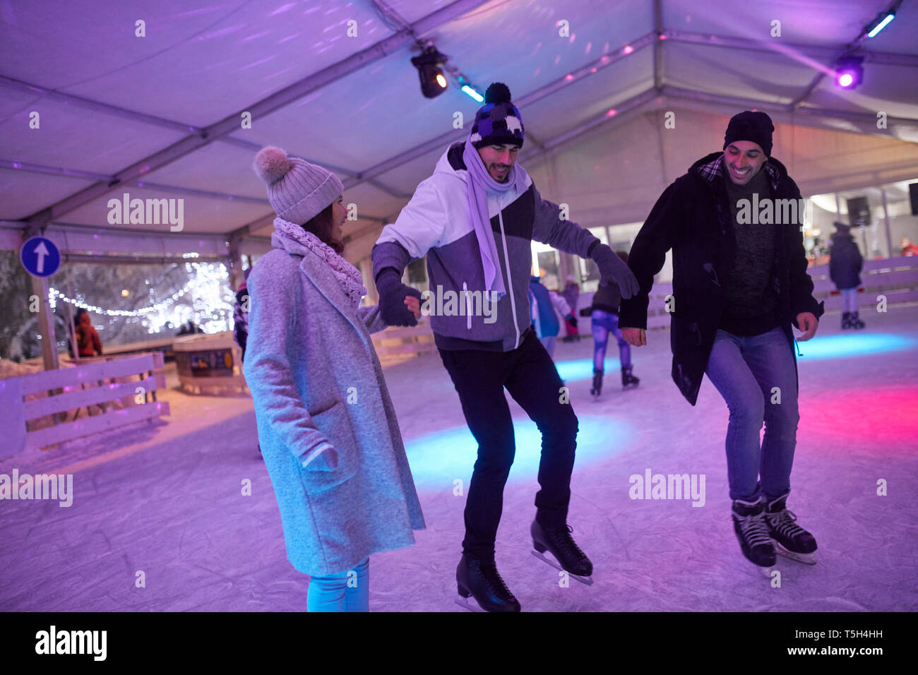 Happy friends ice skating on an ice rink at night Stock Photo - Alamy