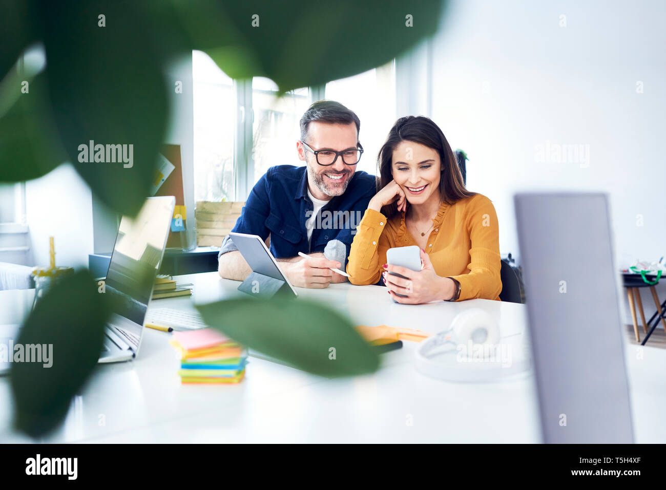Two colleagues working together on tablet and smartphone in office ...