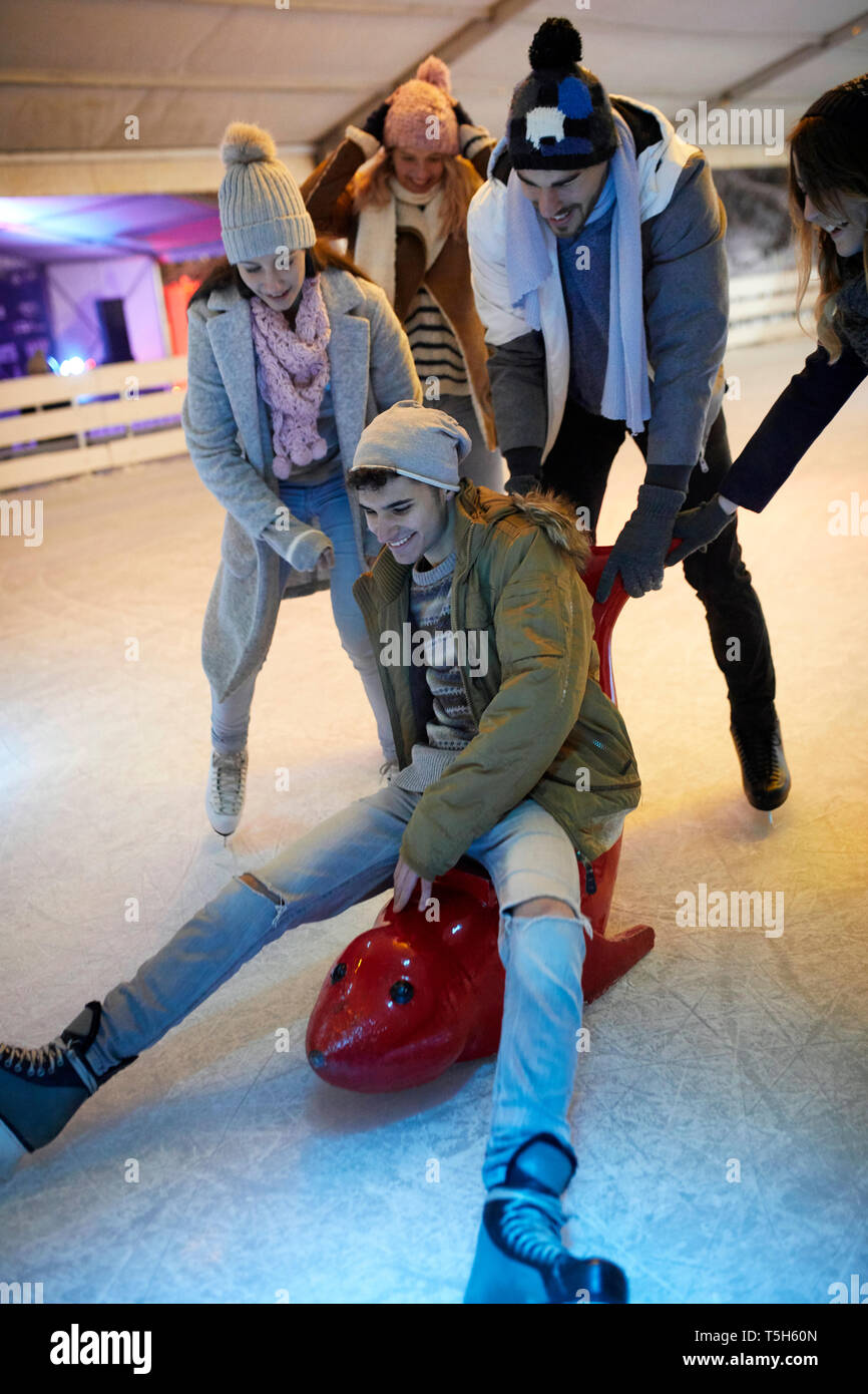 Happy playful friends ice skating on an ice rink Stock Photo - Alamy