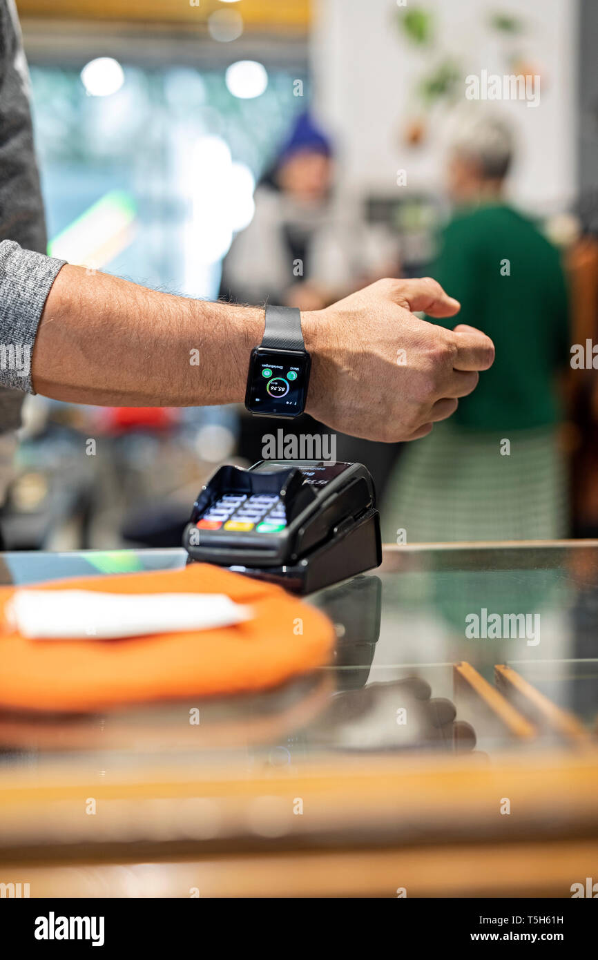 Customer paying contactless with his smartwatch Stock Photo - Alamy