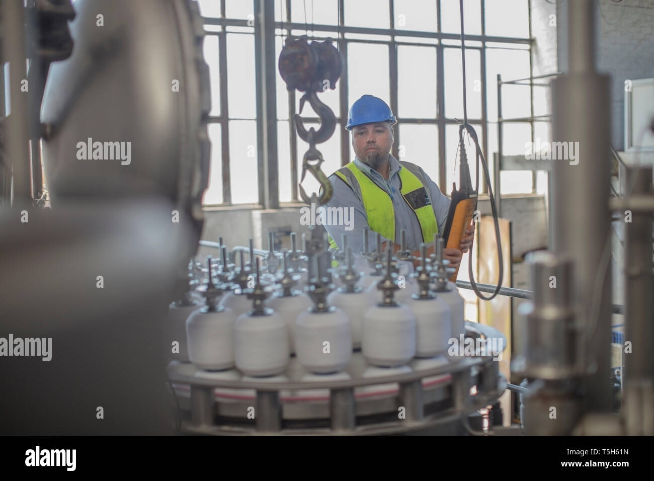 Man wearing hard hat operating control in factory Stock Photo - Alamy