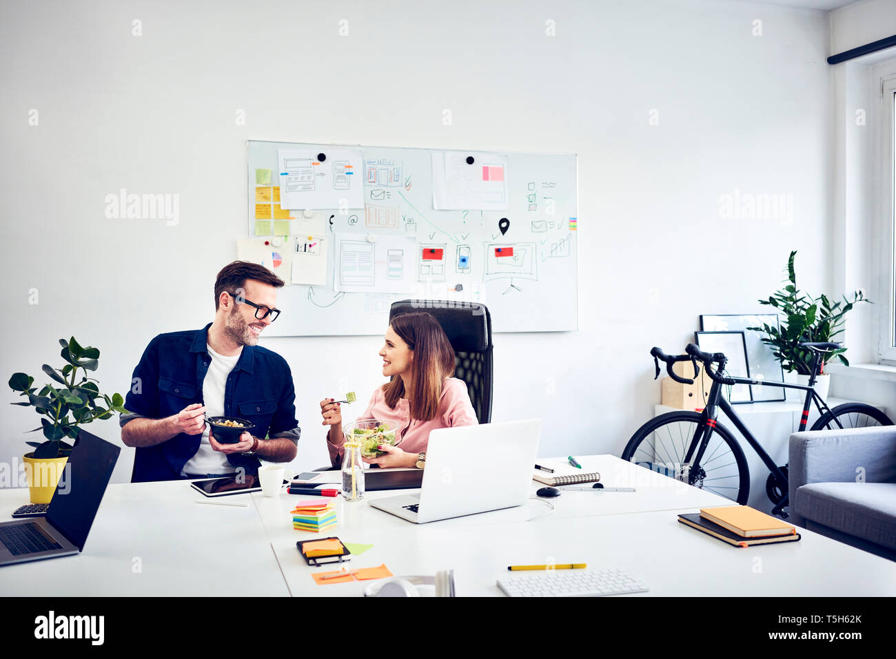 Two colleagues talking during lunch break in office Stock Photo - Alamy