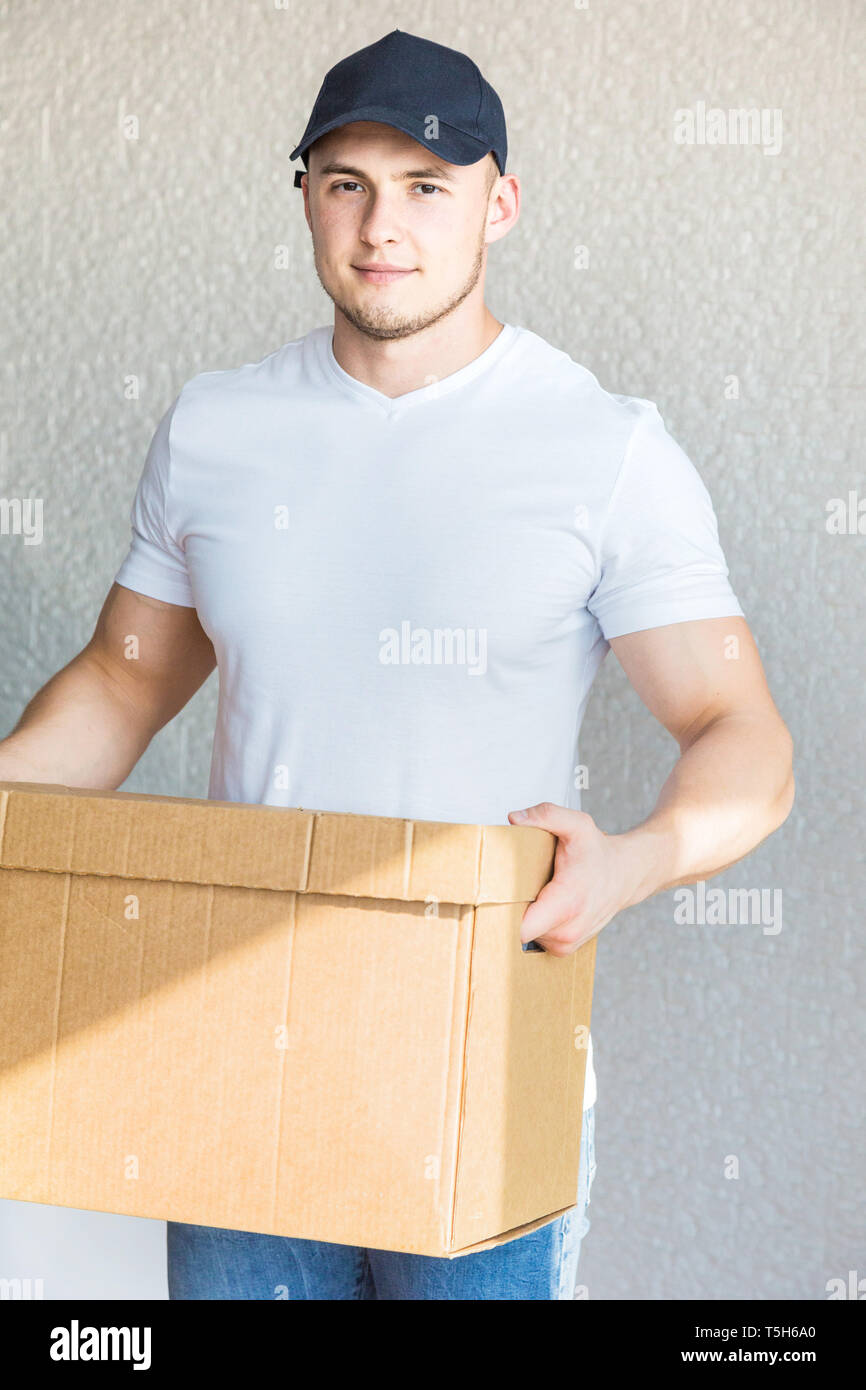 Delivery strong, muscular man loading cardboard boxes for moving to an ...