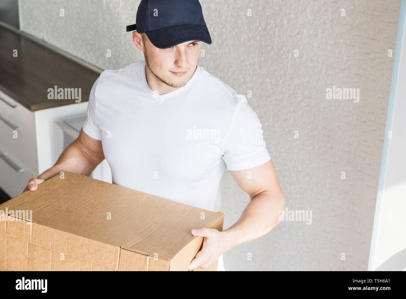 Delivery strong, muscular man loading cardboard boxes for moving to an ...