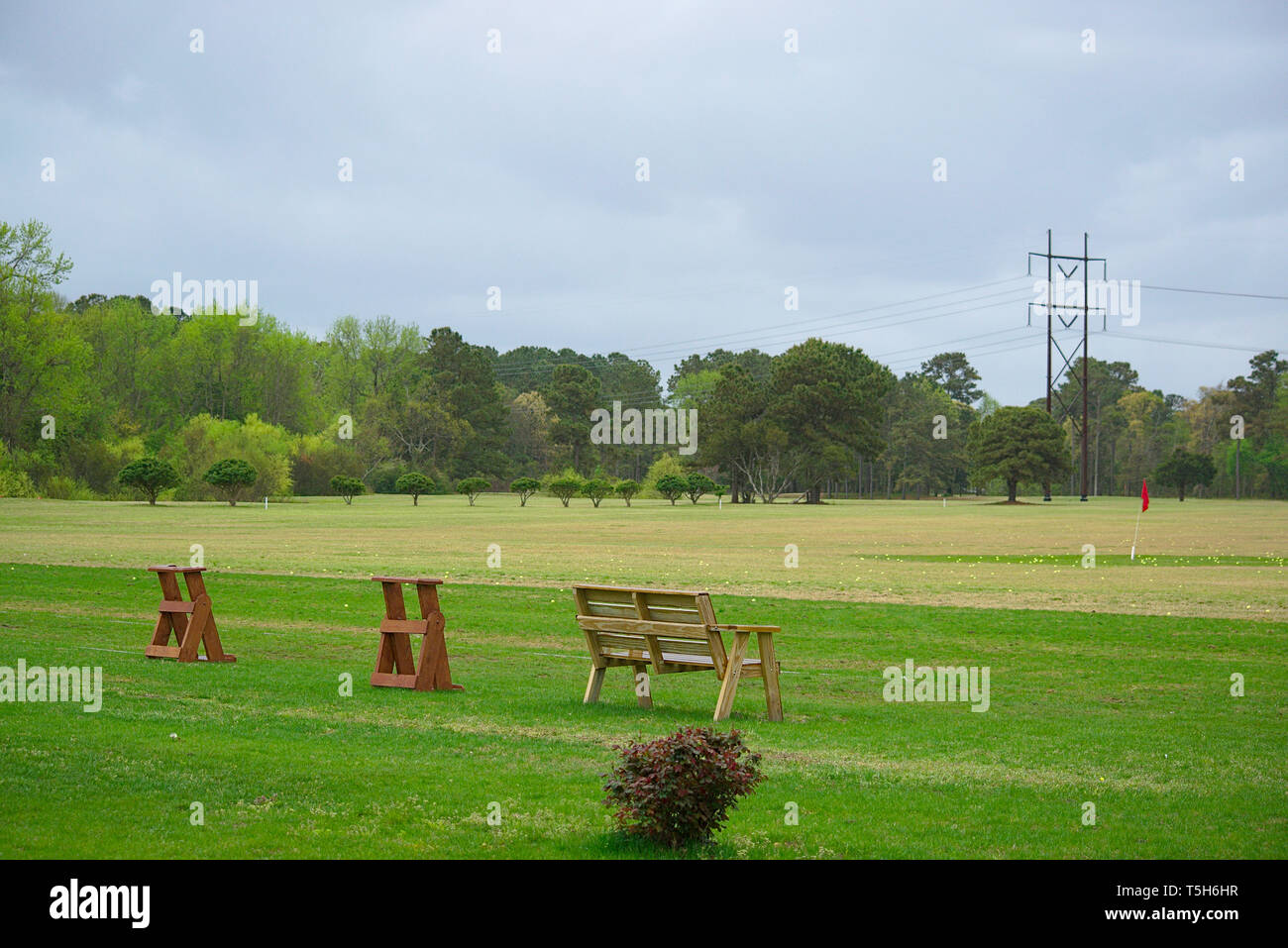 Golf driving range with wooden bag stand and bench Stock Photo - Alamy