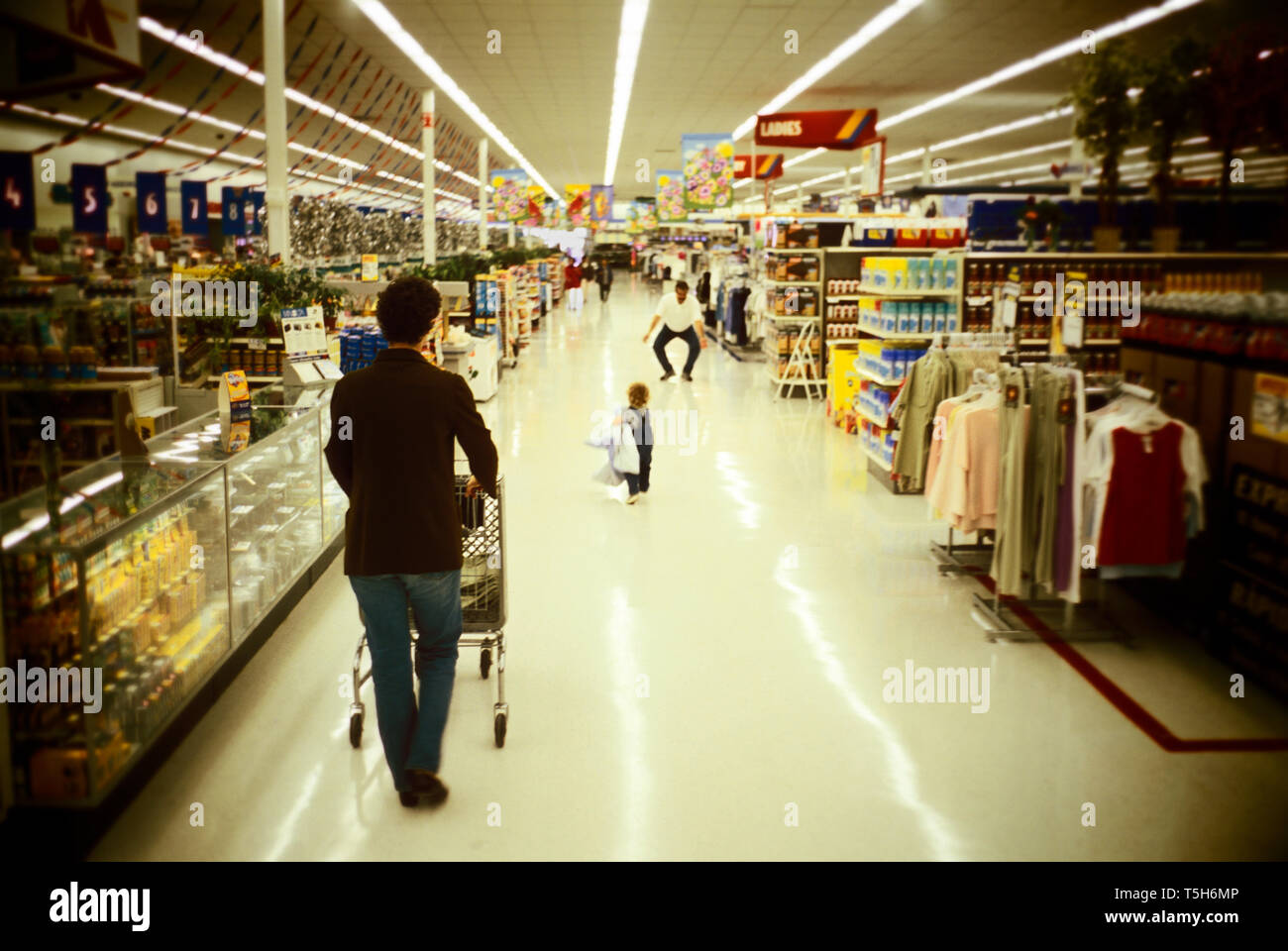 Rear view of a woman pushing a shopping cart inside a supermarket Stock ...