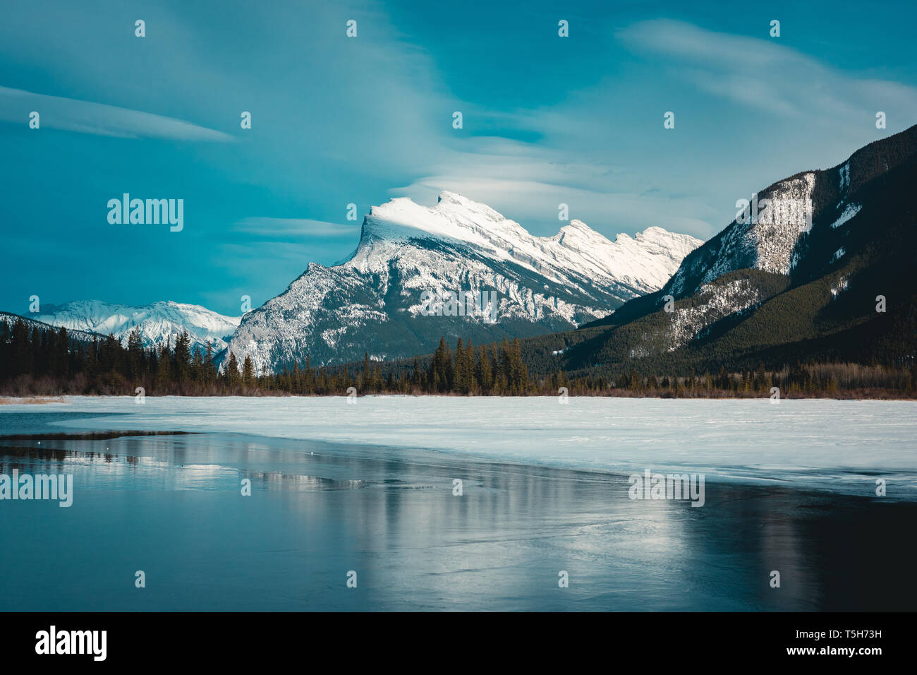 Panorama of Mount Rundle mountain peak with blue sky reflecting in ...